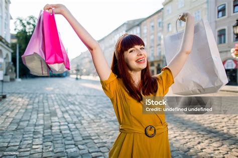 매력적인 젊은 백인 빨간 머리 여자의 야외 초상화를 닫고 팔을 들고 도시 거리를 걷고 좋은 쇼핑 후 만족 화려한 종이 가방을 들고 3 명에 대한 스톡 사진 및 기타 이미지