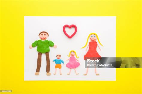 하얀 종이에 화려한 모델링 점토로 만든 인간과 심장 모양 밝은 노란색 테이블 배경 근접 촬영 행복한 사랑의 가족 개념 하향식
