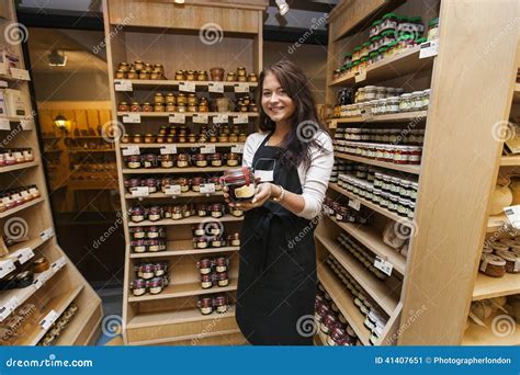 Retrato Da Vendedora Feliz Que Mostra O Produto Na Mercearia Imagem De Stock Imagem De Olhar
