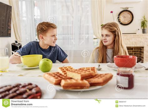 Niños Alegres Que Comen La Comida En Cocina Imagen De Archivo Imagen