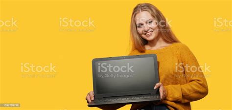 노란 배경 위에 빈 화면으로 노트북을 들고 아름다운 금발의 젊은 여자 미소 공간을 복사합니다 백인 여성은 모의와 함께 앞으로