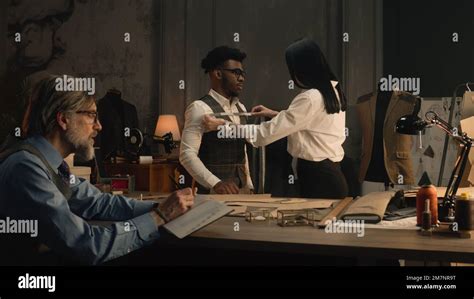 Female Tailor Measures African American Client Discusses With Male