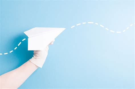 흰색 고무 장갑에 손을 잡고 밝은 파란색 배경에 종이 비행기를 보유하고 공간을 복사 코로나 바이러스 전염병 개념으로 인한 수혈