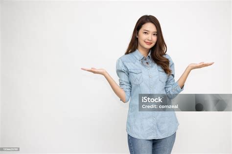 청바지 셔츠를 입고 제시하고 흰색 배경에 고립 된 제품을위한 복사 공간이있는 오픈 핸드 팜을 보여주는 행복한 아시아 여성 광고에