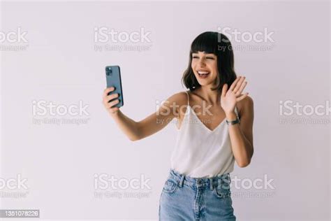 흰색 배경에서 고립된 비디오 통화 중에 스마트 폰을 흔들고있는 젊은 여성 십대에 대한 스톡 사진 및 기타 이미지 십대