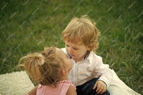 Premium Photo Sister Kiss Brother With Blond Hair On Green Grass