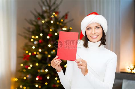 节日庆祝人们的微笑的女人戴着诞帽着贺卡诞树背景带着贺卡的微笑的女人诞节高清图片下载 正版图片300160313 摄图网