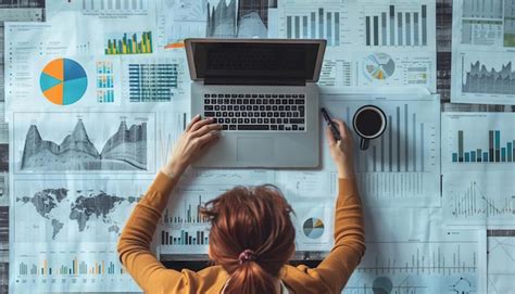 An Overhead View Of A Data Analyst Using A Laptop Surrounded By Graphs