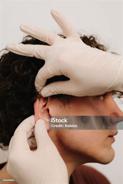 외과 의사가 귀 성형 수술 전에 남성 환자의 귀를 검사합니다 귀 성형 수술 전 준비 귀의 모양 위치 또는 크기를 변경하는 절차 20 24세에 대한 스톡 사진 및 기타 이미지