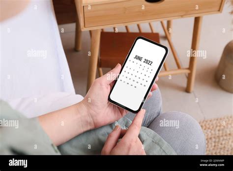 Woman With Modern Mobile Phone Using Calendar Application At Home Stock