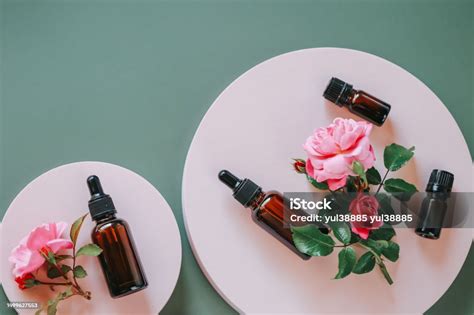 장미 물 회색 배경에 분홍색 연단에 있는 유리병에 담긴 장미 기름 위에서 본 모습 아로마 테라피와 화장품 유기농 천연 로즈 오일
