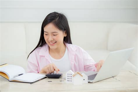 젊은 아시아 여성은 앉아서 계산기와 책상에 집 주거 및 대출 및 주택 비즈니스 및 재산 개념의 보험 및 예산으로 비용과 모기지를