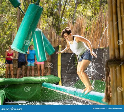 Happy Brunette Crossing Pool Of Water On Inflatable Log With Hanging