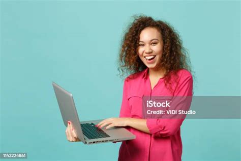 스튜디오에서 파란색 청록색 벽 배경에 고립 된 노트북 Pc 컴퓨터를 사용 하 여 분홍색 캐주얼 옷에 웃는 아프리카 소녀의 초상화