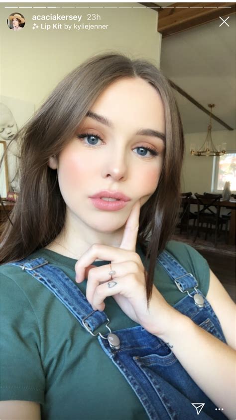 A Woman With Long Brown Hair Wearing Overalls And A Ring On Her Finger