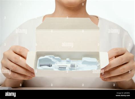 A Closeup Of Female Hands Holding A Package Box With A Syringe Of