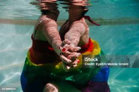 Lesbian Couples With Rainbow Flags Holding Hands In Swimming Pool Stock