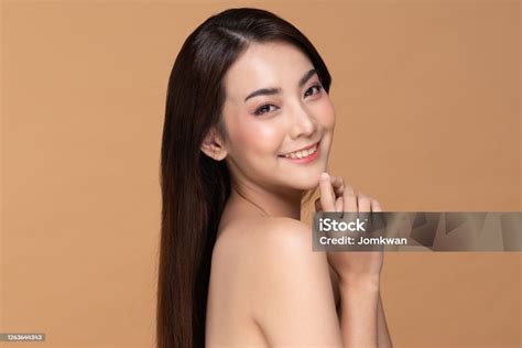 깨끗하고 신선한 피부행복과 유쾌한 감성으로 턱미소를 만지는 아름다운 아시아 여성 베이지 색 배경 뷰티 코스메틱 스파 페이셜