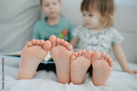 Big Brother And Little Sister Holding Bare Feet Close Up To Camera