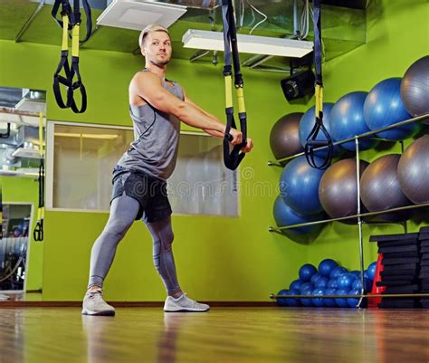 Blond Athletic Male Doing Trx Straps Exercises In A Gym Club Stock