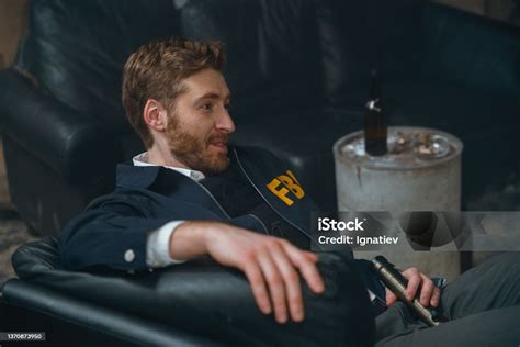 Handsome Fbi Agent Sitting In A Black Armchair At The Crime Scene In