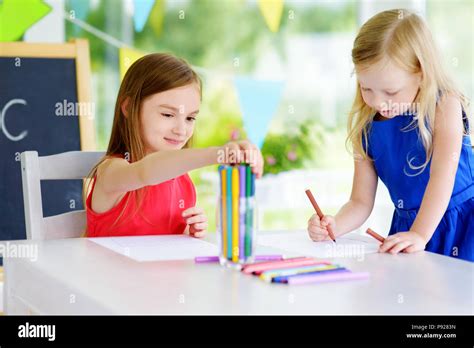 Two Cute Little Sisters Drawing With Colorful Pencils At A Daycare