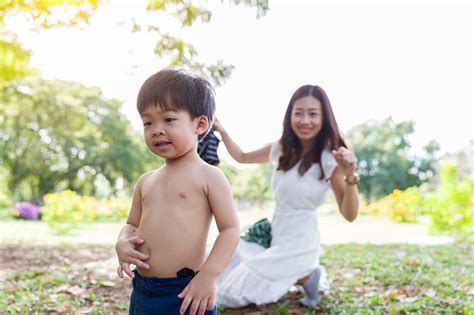 아시아인 어머니는 티셔츠를 벗고 공원에서 야외에서 어린 아들과 놀고 있습니다 쾌활한 어머니는 놀고 재미와 야외 휴일에 작은