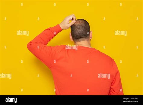 Back View Of Thoughtful Man Scratching His Head Over Yellow Background