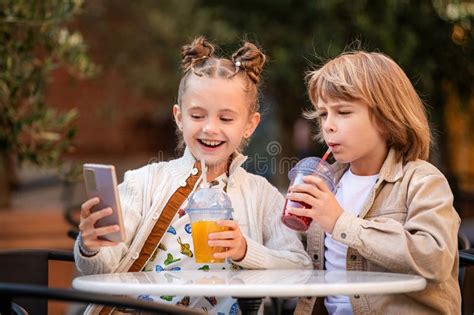 Two Happy Friends Playing Together In The Summer Park And Drinking