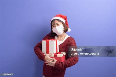 빨간 산타 클로스 모자 고립 된 파란색 배경 스튜디오를 입고 수술 마스크를 착용 젊은 미소 여자의 초상화 12월에 대한 스톡 사진 및 기타 이미지 Istock