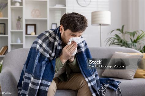 담요에 싸여 집에서 아픈 남자를 휴지로 재채기하고 질병 추위 독감 및 가정 환경에서의 편안함에 대한 개념을 포착합니다 질병에 대한 스톡 사진 및 기타 이미지 Istock