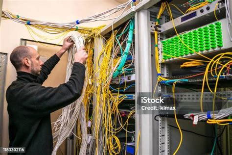 시스템 관리자가 서버 랙에 새 케이블 통신을 배치하고 있습니다 남자는 데이터 센터의 크로스 패널에 와이어를 전환합니다 기술자는 서버룸에서 작동합니다 광섬유의에 대한 스톡