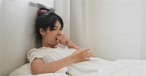 아픈 여자는 침실의 침대에 누워있는 동안 물을 마시고 알약을 먹습니다 사진 Unsplash의 태국 이미지