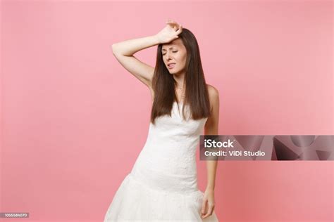 하얀 웨딩 드레스를이 마에 손을 유지 분홍색 배경에 고립 된 결혼식을 위해 준비의 피곤에 지친된 신부 여자의 초상화 결혼식 축