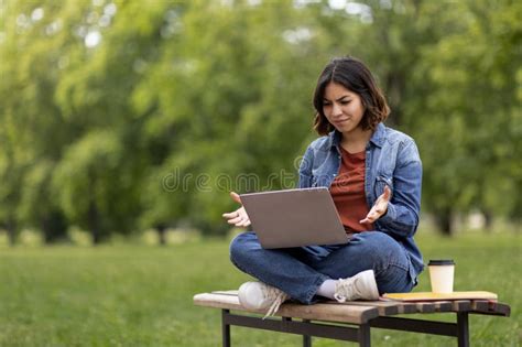 Confused Arab Woman Having Problem With Laptop While Sitting On Bench