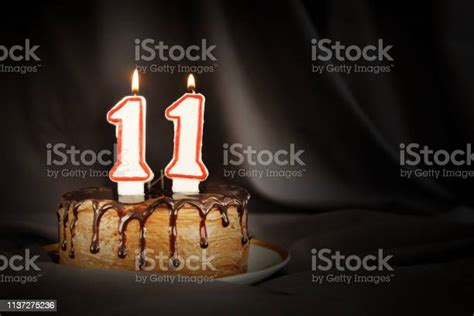 11 년 기념일 숫자 일레븐의 형태로 흰색 불타는 촛불 생일 초콜릿 케이크 검은 천으로 어두운 배경 11에 대한 스톡 사진 및