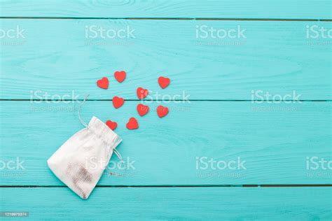 파란색 나무 배경에 흰색 실버 드로스트링 가방입니다 발렌타인 하트가 있는 패브릭 코튼 스몰 백 보석 파우치 맨 위 보기 공간을 복사하고 조롱합니다 가득 찬에 대한 스톡 사진