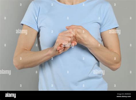 Woman Cracking Her Knuckles On Light Grey Background Closeup Bad