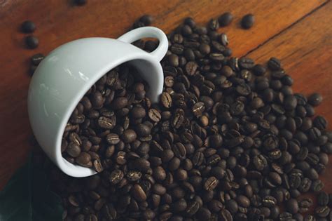 화이트 커피잔과 커피 콩 아름 답게 배열 나무 테이블에 Poured 커피 잎으로 장식 커피를 만들기 위한 원료의 혼합 0명에