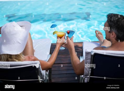Rear View Of Couple Toasting Martini Glass While Relaxing On Sun
