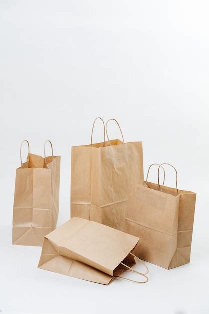Quatro sacos de papel marrom vazios dispostos em uma composição sobre fundo branco um está