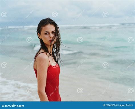 Woman With Wet Hair In Red Swimsuit On Oceanfront Sunbathing Stock