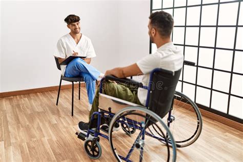 Two Hispanic Men Physiotherapist And Patient Sitting On Wheelchair