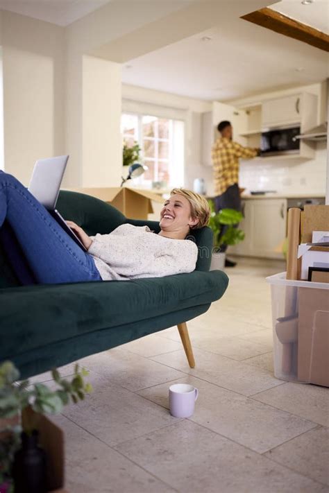 Couple Unpacking Boxes After Moving Into New Home Together As Woman