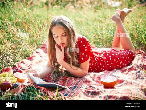 Picnic Scene Pretty Girl Lying On A Plaid And Reading Book In Grove