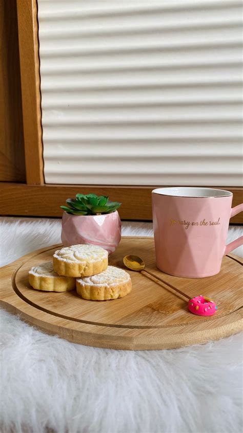 A Wooden Tray Topped With Pastries And A Pink Coffee Cup Next To A Window
