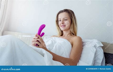 Young Woman In The Bed Holding In Her Hands A Sex Toy For Adults Stock