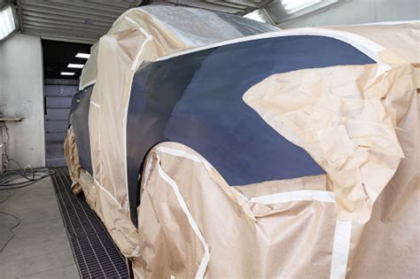 대형 블랙 카는 완전히 종이와 접착 테이프로 덮여 있어 밝은 조명이 있는 차량의 차체 수리를 위한 워크샵에서 사고 후 페인팅 및 수리 중 스플래시를 방지 합니다 가리기에