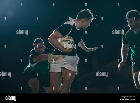 Rugby Player Running With Ball And Tackling Opponents During Match