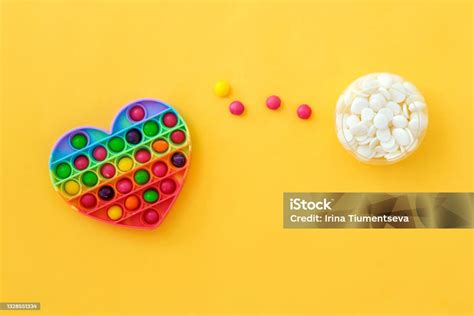 인기 팝 토이를 초콜릿 몰드로 사용하십시오 컬러풀한 사탕은 노란색 배경에 팝 하트의 형태로 실리콘 형태로 놓여 있습니다 Diy